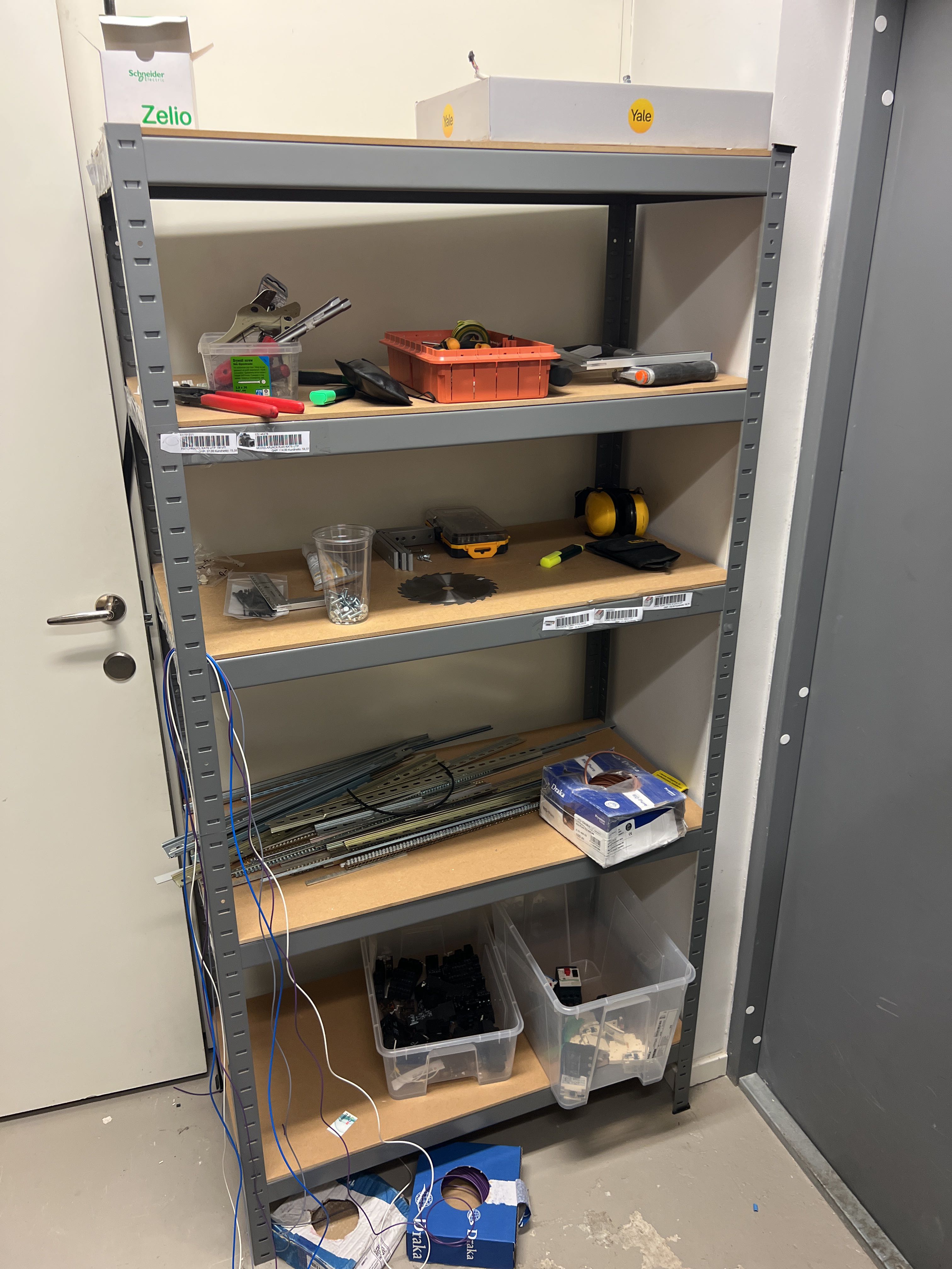 Metal shelves with various electrical installation details and tools ...